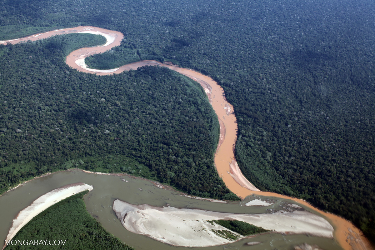 Mine waste-laden stream flowing into a rainforest river in Peru